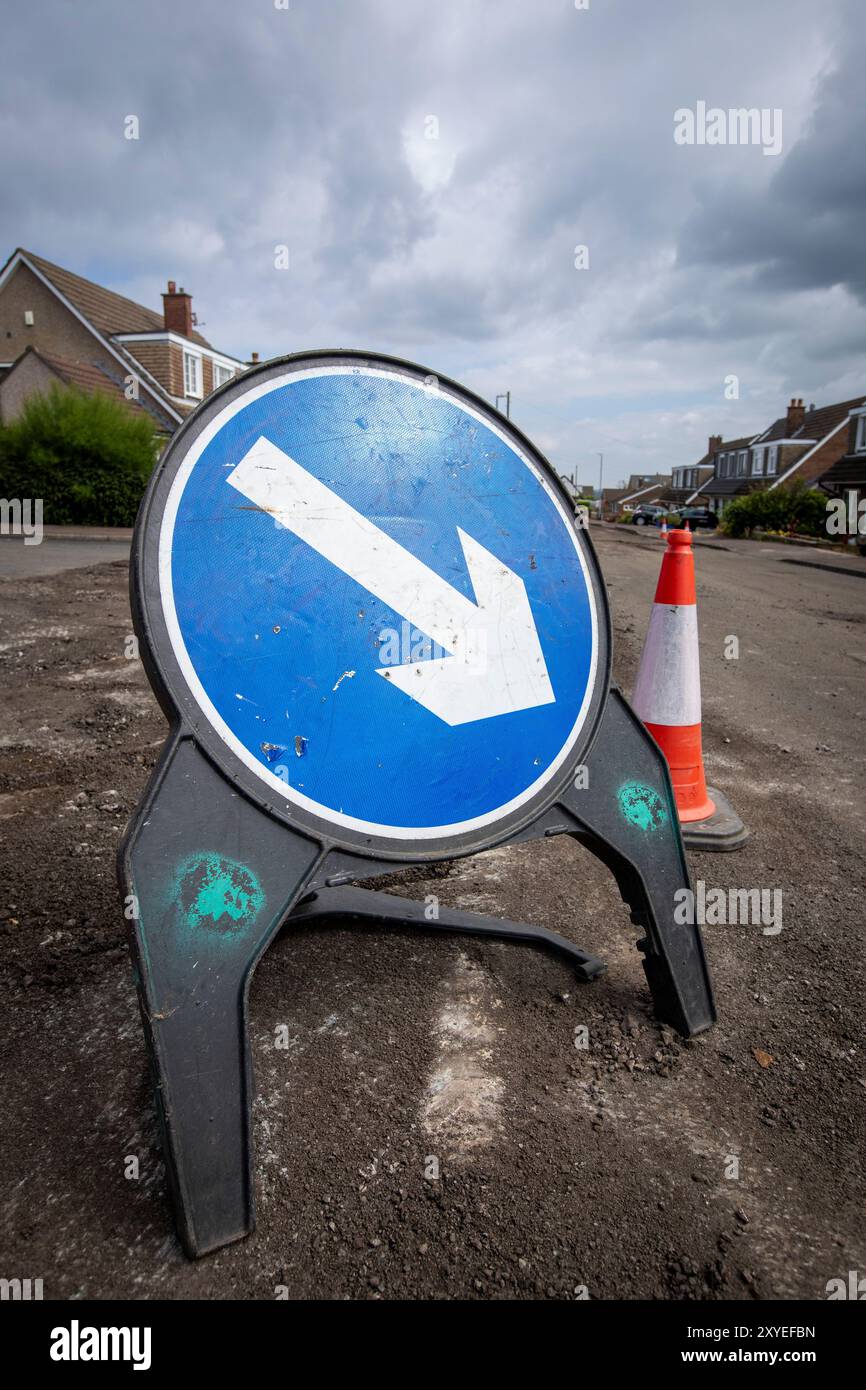 A road warning sign with a white arrow on a circular blue background as ...