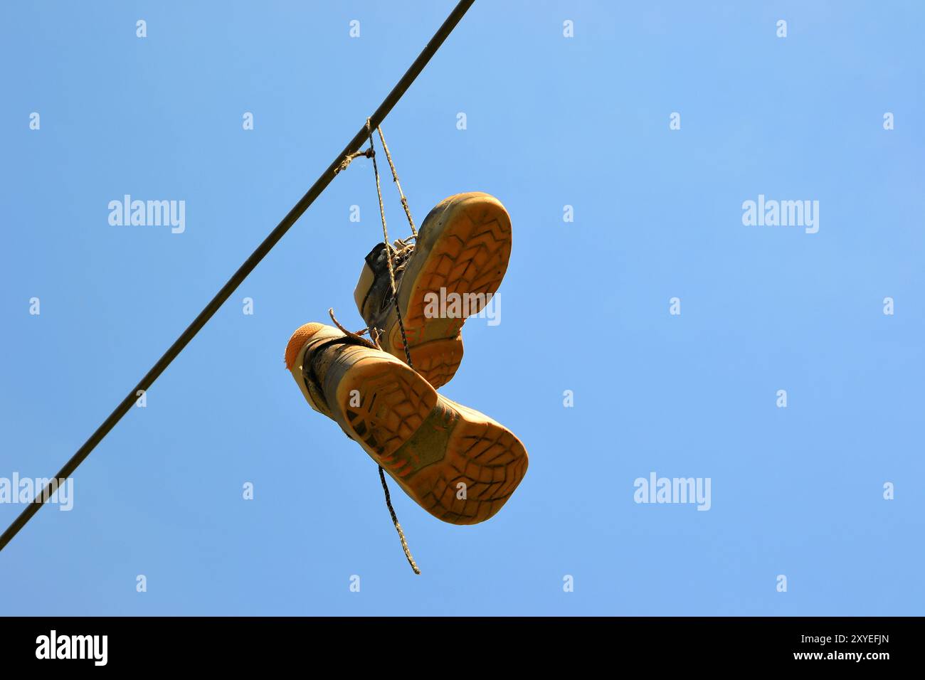 Shoes hanging from an overhead line at a great height Stock Photo - Alamy