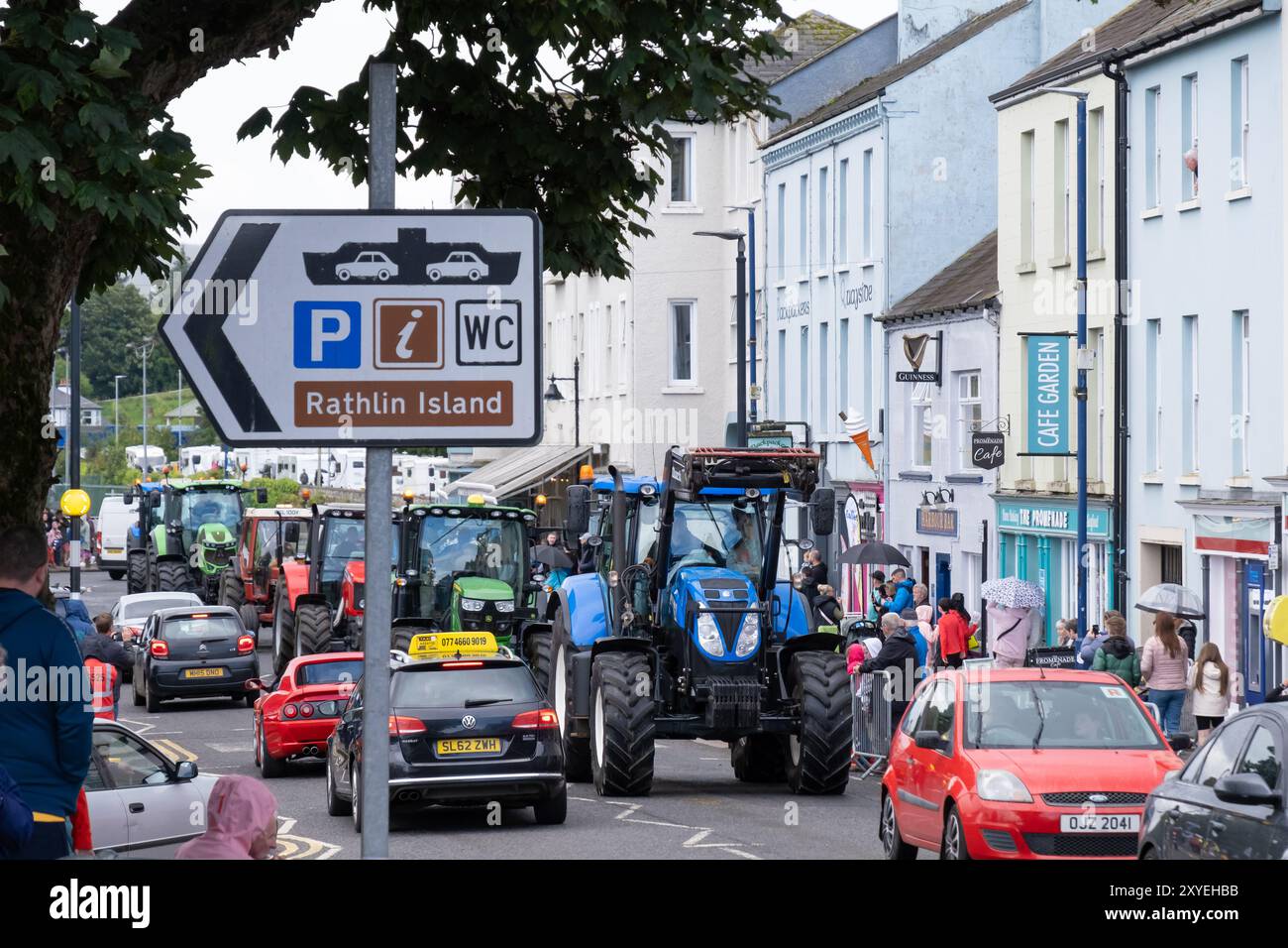 Queue of tractors stretching down street at seafront as vintage tractor ...