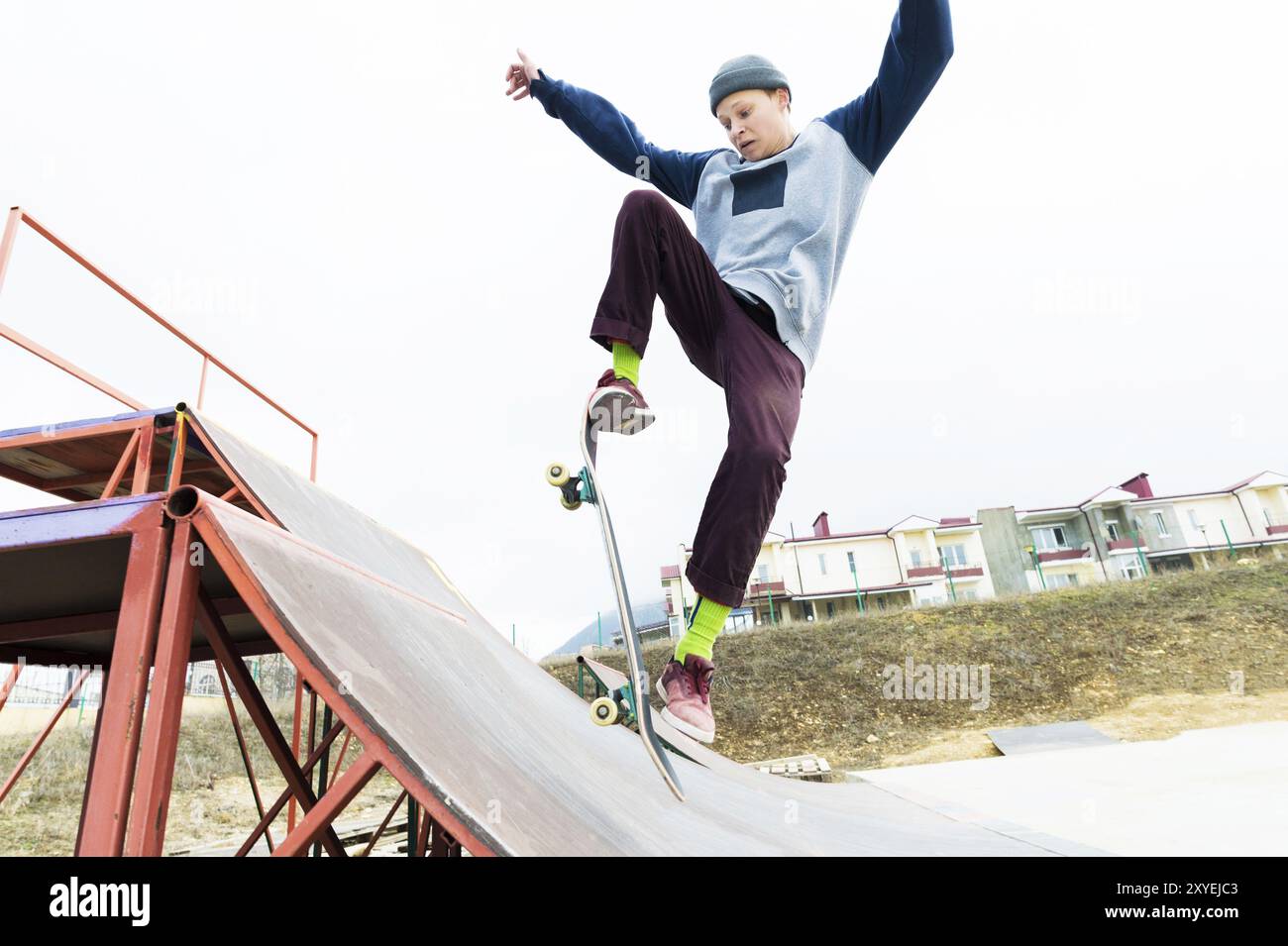 A skateboarder teenager in a hat does a trick with a jump on the ramp ...
