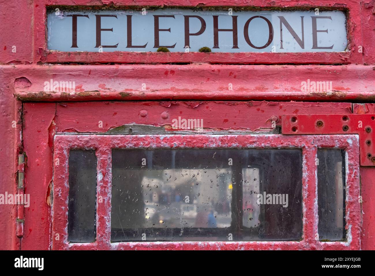 Old red British public telephone box, view of top section, flaking ...