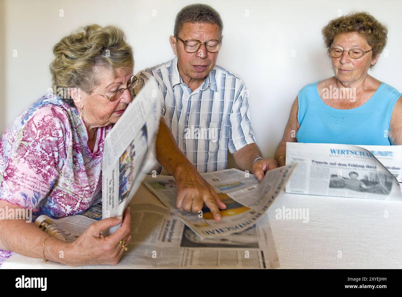 3 senior citizens reading a newspaper Stock Photo - Alamy