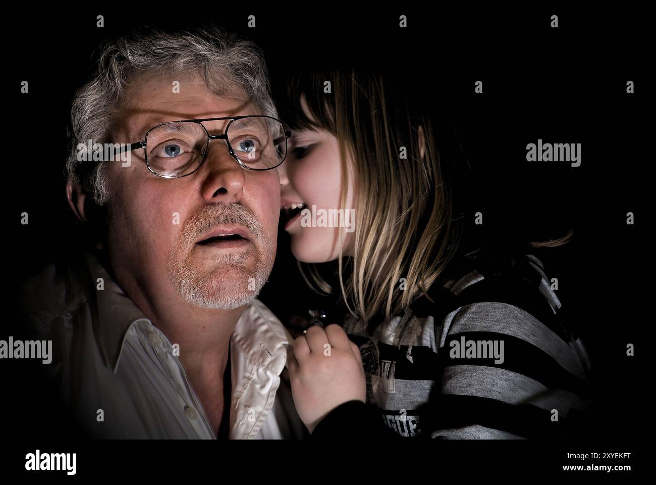 Granddaughter whispers a secret in grandpa's ear Stock Photo - Alamy