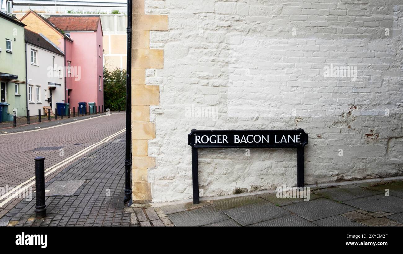 Roger Bacon Lane street sign against a white stone wall and houses ...