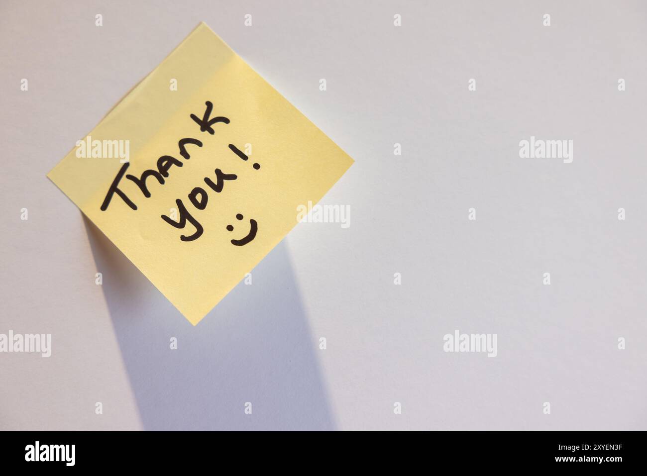 A yellow sticky note with the words "thank you" written on it. The note ...