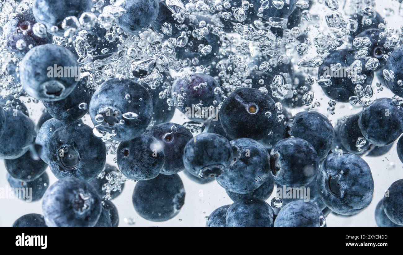 Blueberries sinking into water with air bubbles white background Stock ...