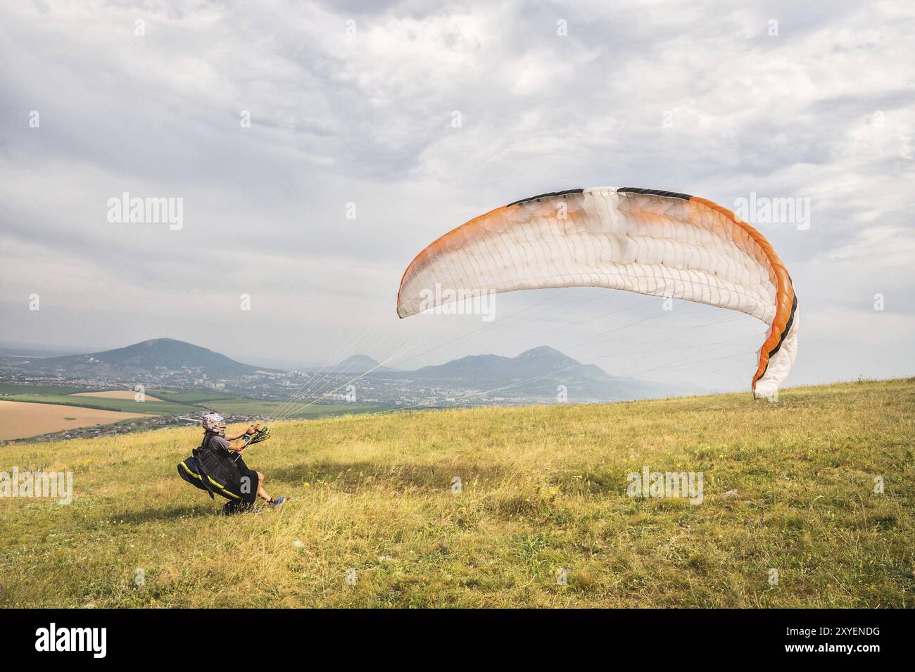 The paraglider opens his parachute before taking off from the mountain ...