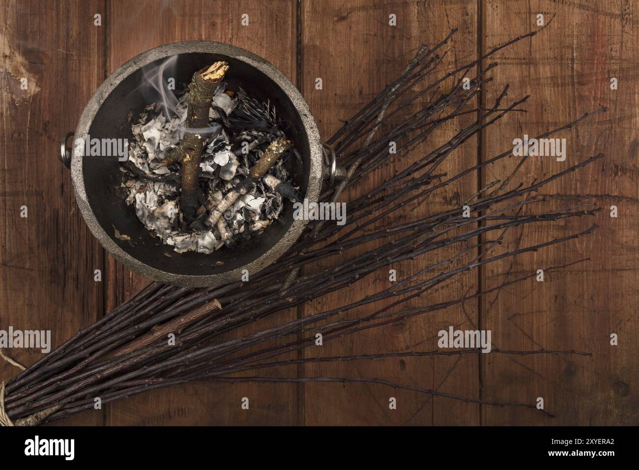An overhead photo of a smoking witch's cauldron with ashes and wooden ...