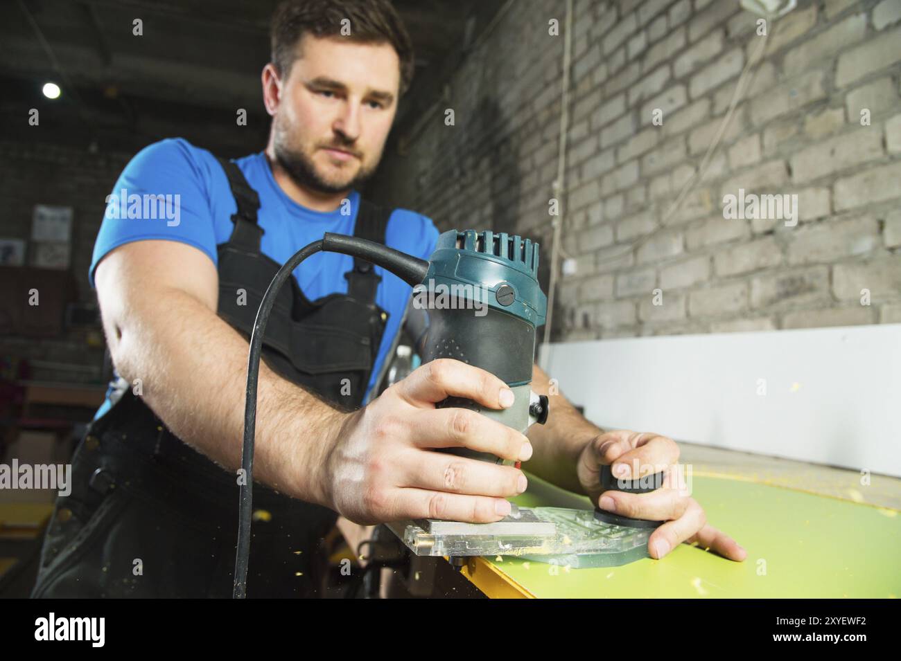 Professional carpenter processes the plastic edges of the countertop ...
