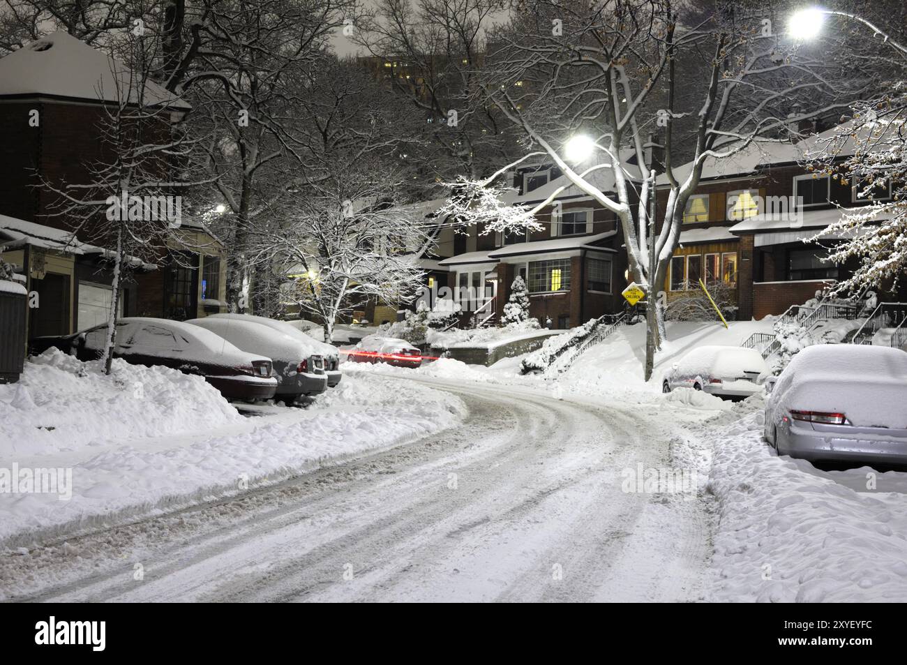 Covered with snow road illuminated with street lights at night And ...