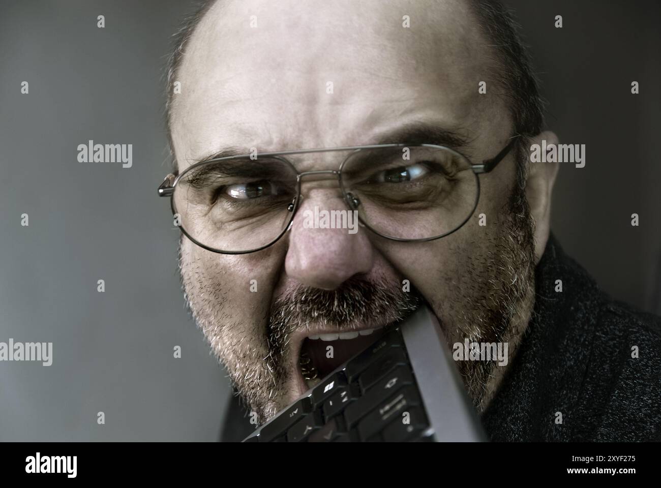 Man bites angrily into a keyboard Stock Photo - Alamy