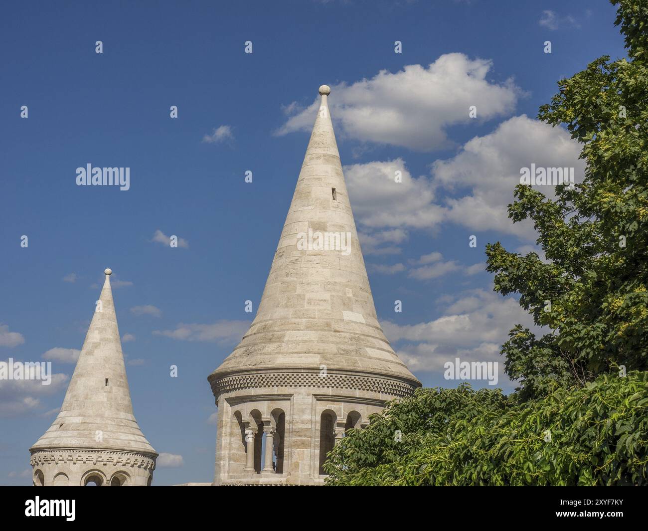 Historic stone towers rise into a blue sky with scattered clouds ...