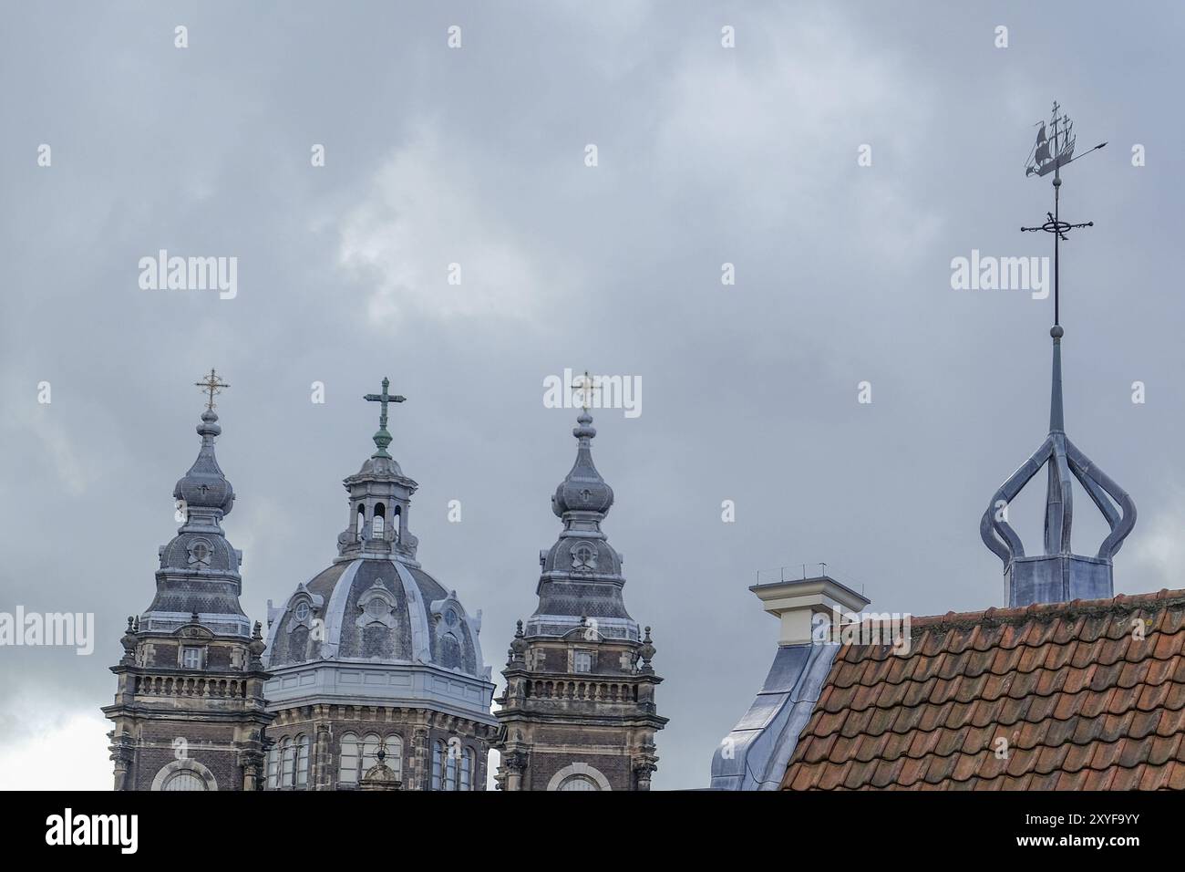Church spires and a roof with weather vane under a cloudy sky ...