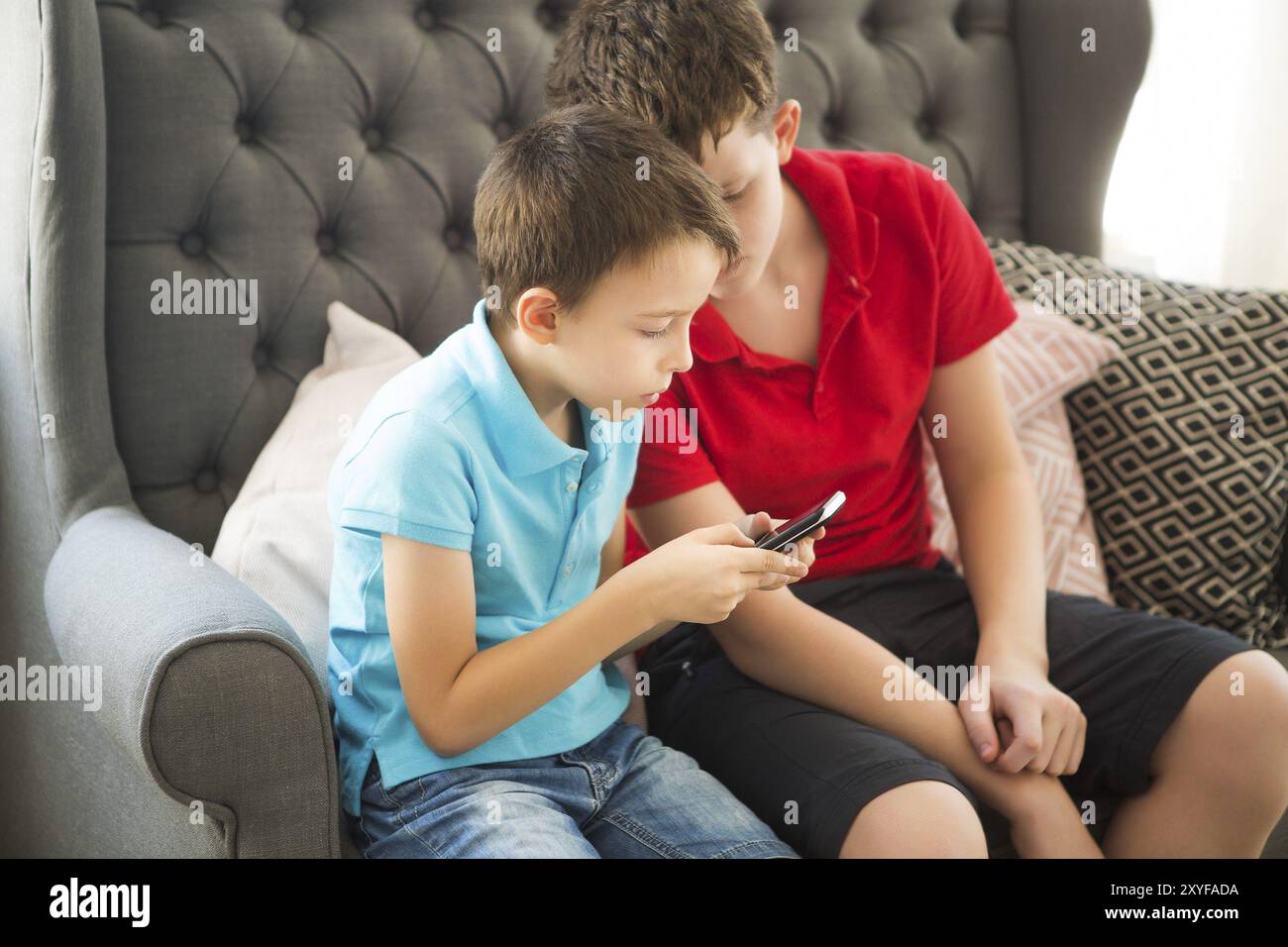 Older brother on the sofa and younger brother playing mobile phone ...
