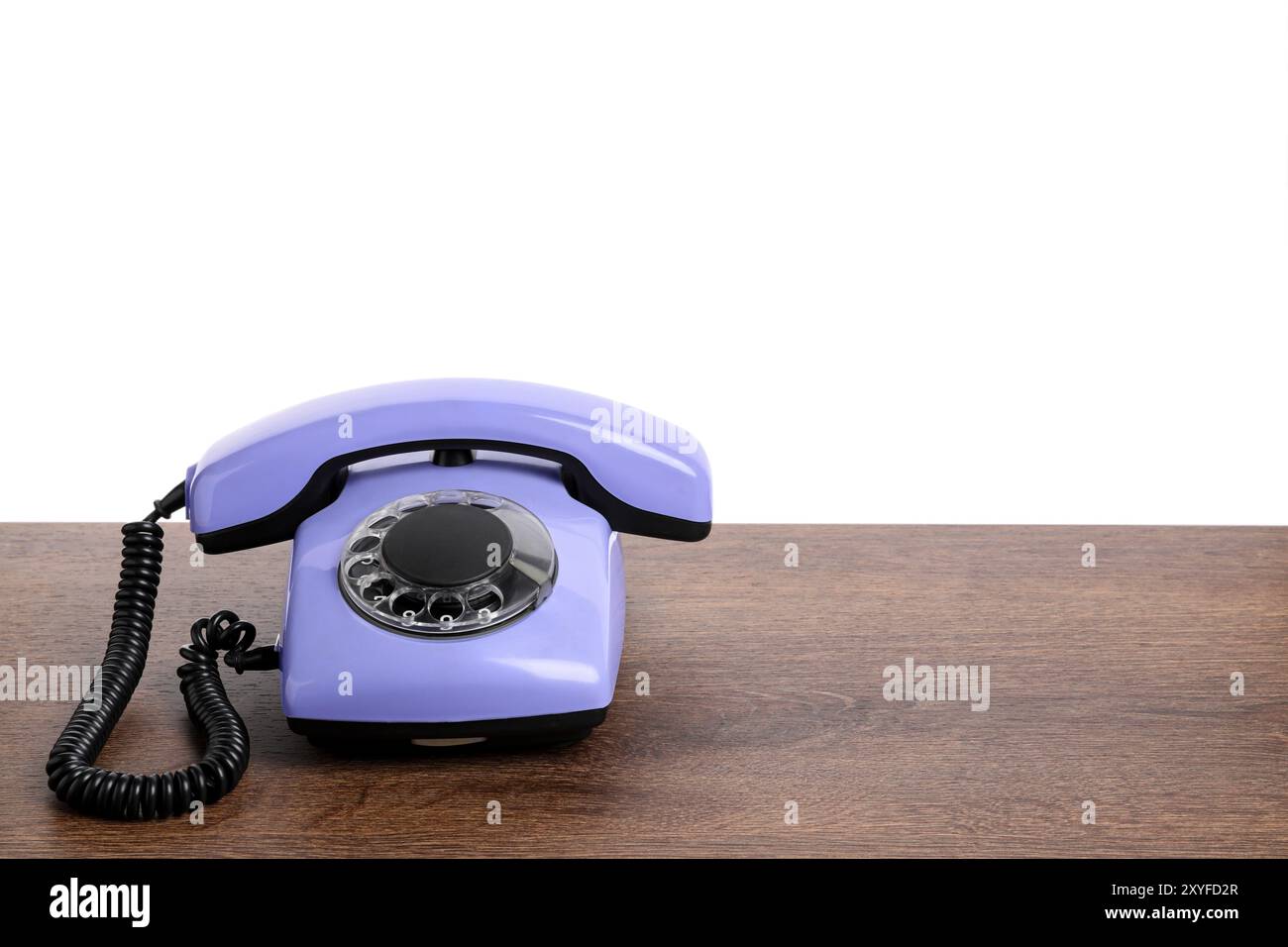 One violet telephone with handset on wooden table against white ...