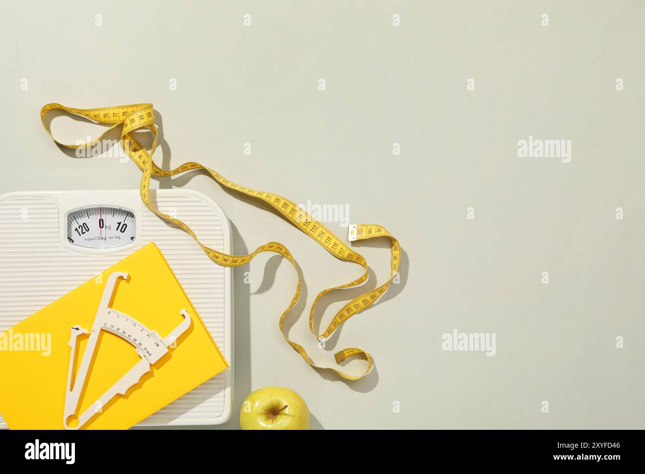 Body fat caliper, measuring tape, scale and notebook on light grey ...