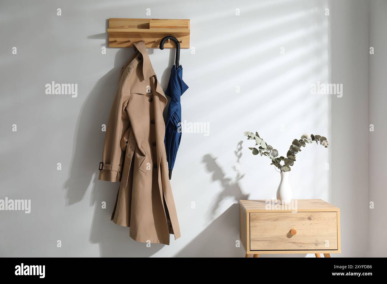 Colorful umbrella and trench coat hanging on rack at home Stock Photo ...