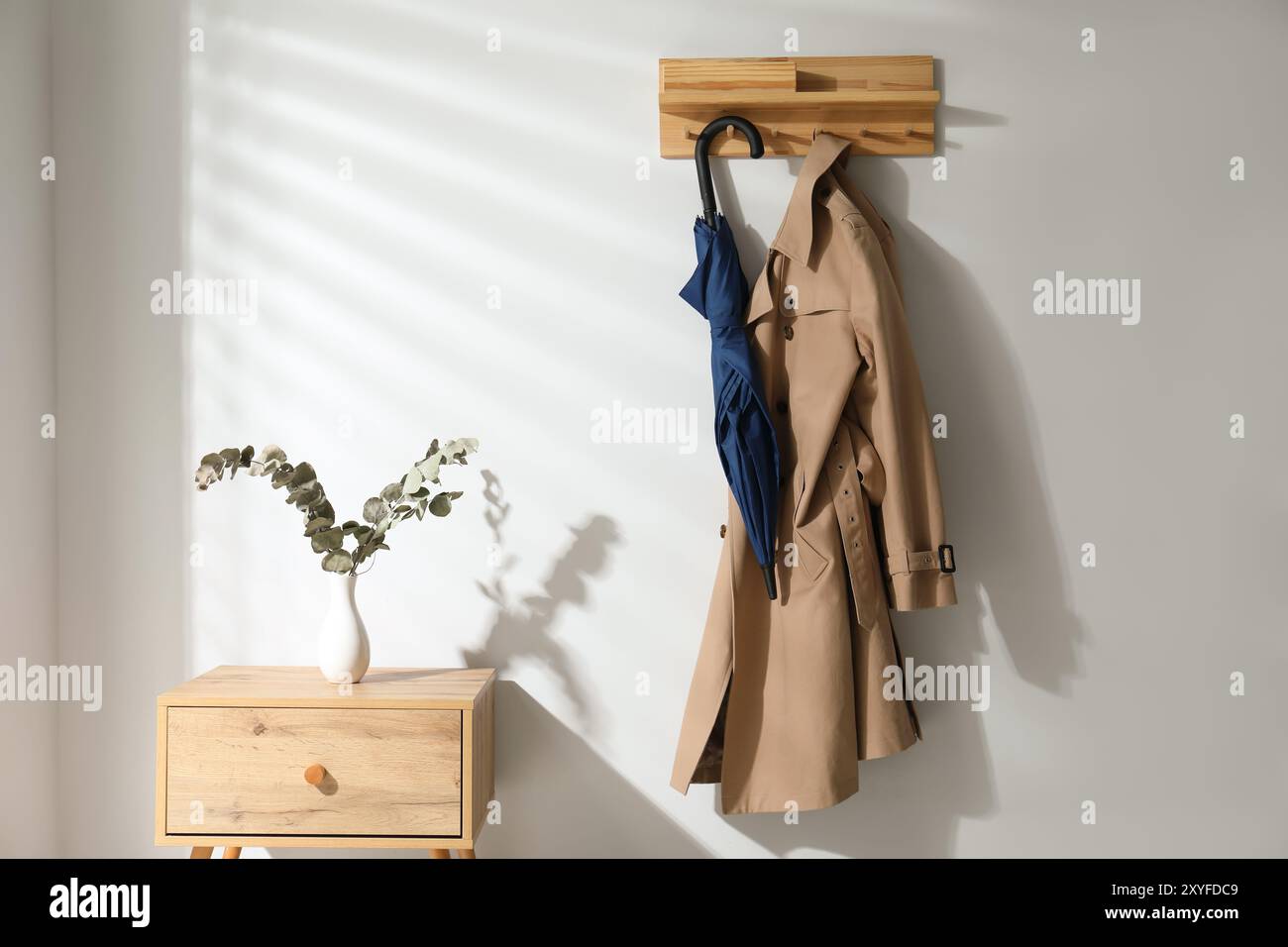Colorful umbrella and trench coat hanging on rack at home Stock Photo ...