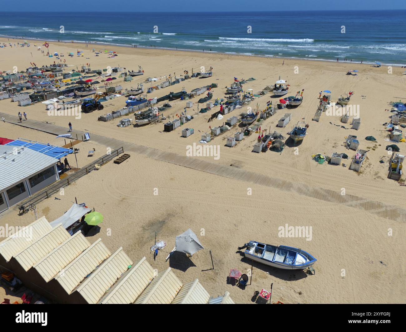 Beach with many boats, huts and parasols. In the background the sea and ...