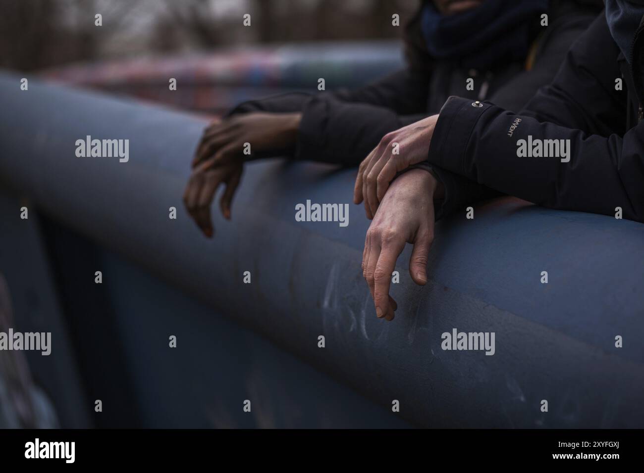Two people place their hands relaxed on a railing Stock Photo - Alamy