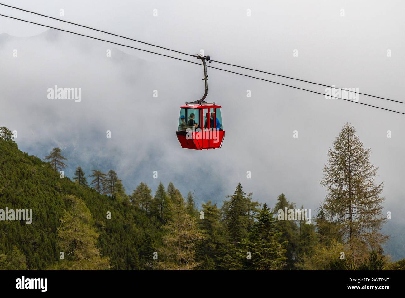red cable car cabin above the trees on a hill in the fog, Katrin cable ...