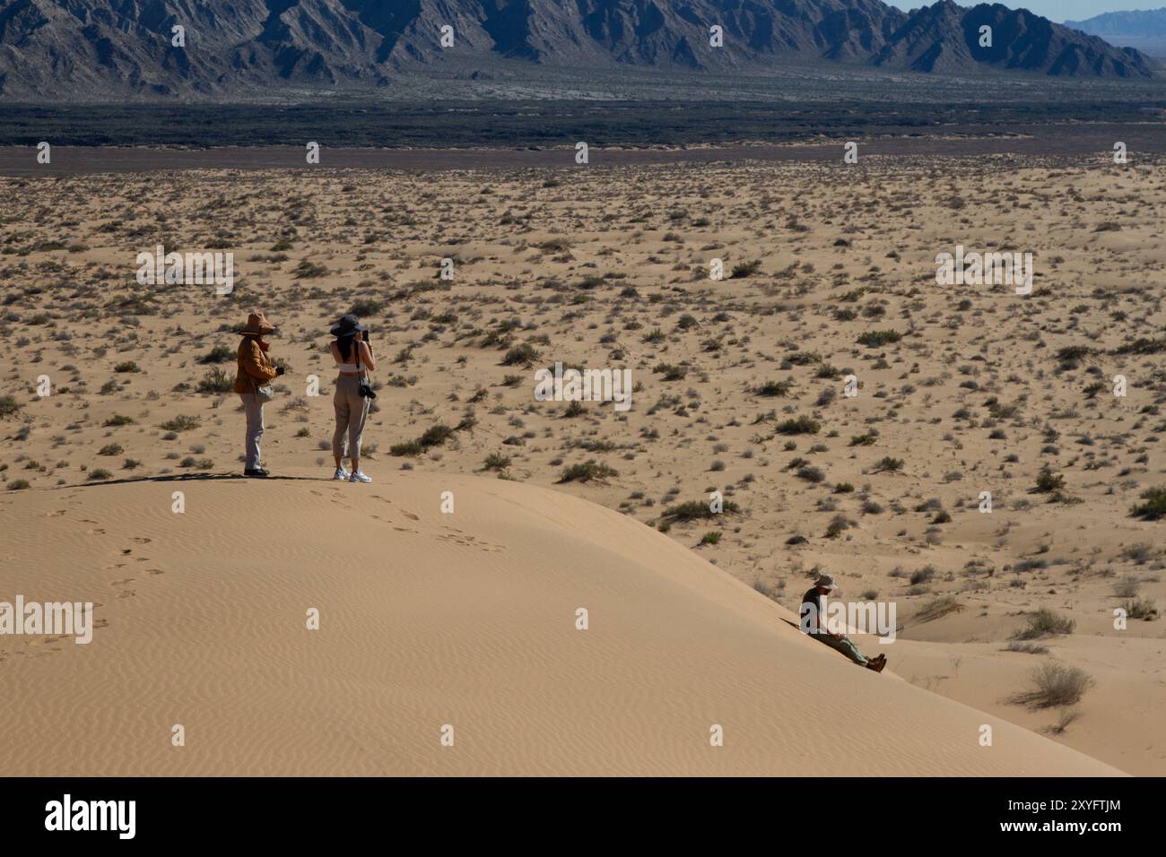 A gruop of three people on the top of a hill in the desert. Desert ...