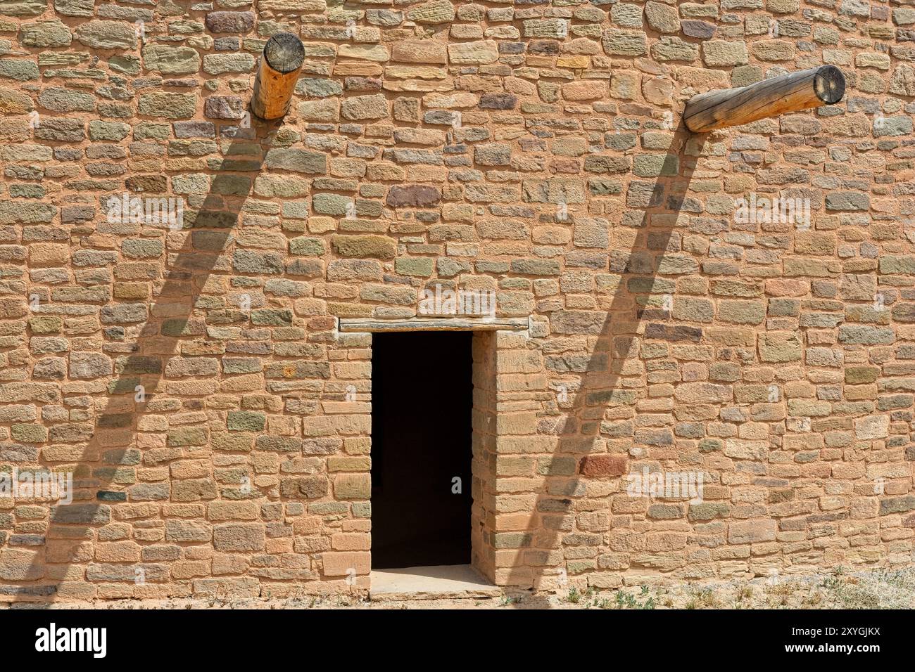 Timber viga beams protrude out of stone masonry walls over doorway to ...