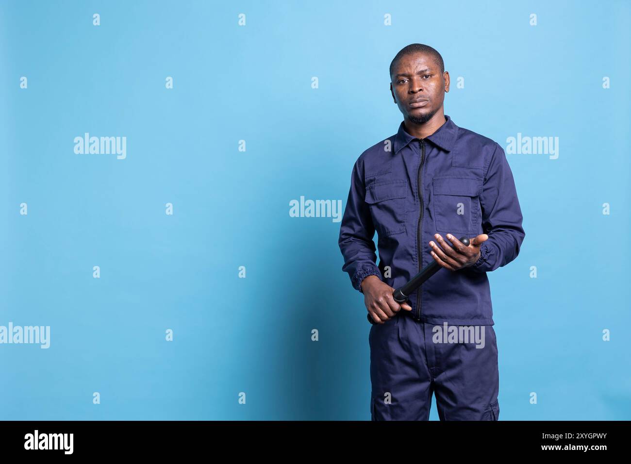 Security officer holding his baton in his hands while on guarding duty ...