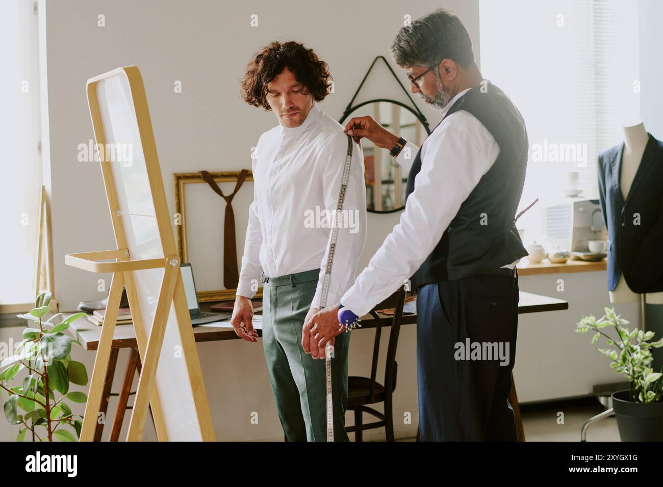 Indian tailor working on customers order while customer standing in ...