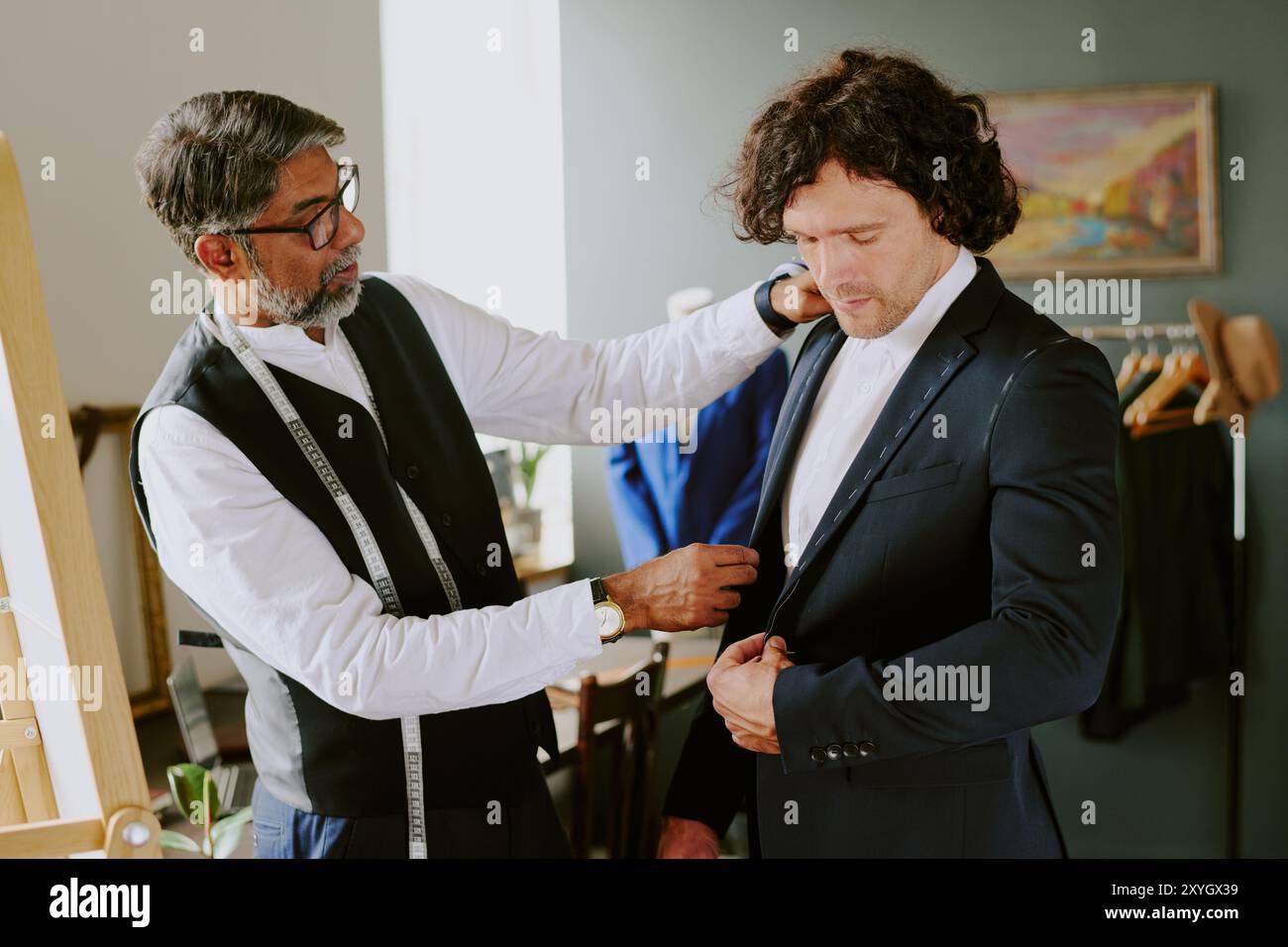 Indian tailor adjusting suit while customer looking at costume in ...