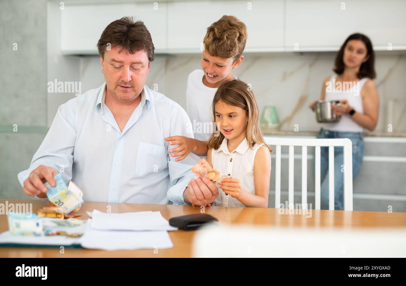 Head of family gives his wife and children pocket money Stock Photo - Alamy