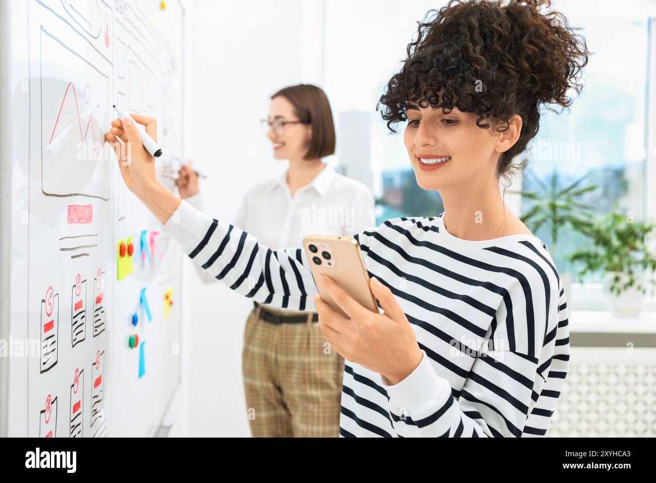 Developing UI design. Women drawing website wireframe on whiteboard ...