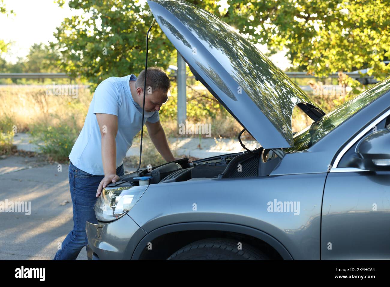 Stressed man looking under hood of broken car outdoors Stock Photo - Alamy