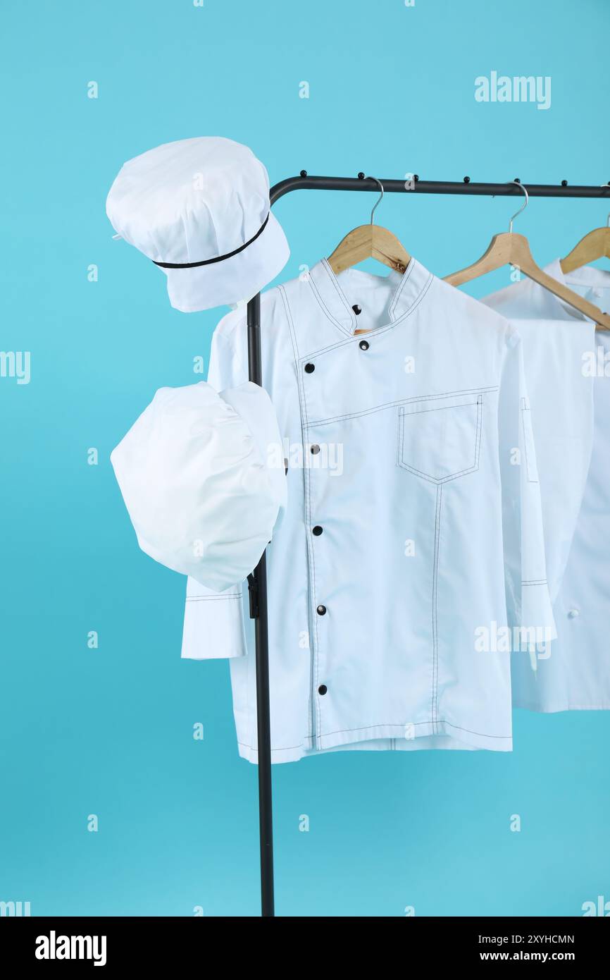 Different chef's uniforms on clothing rack against light blue ...