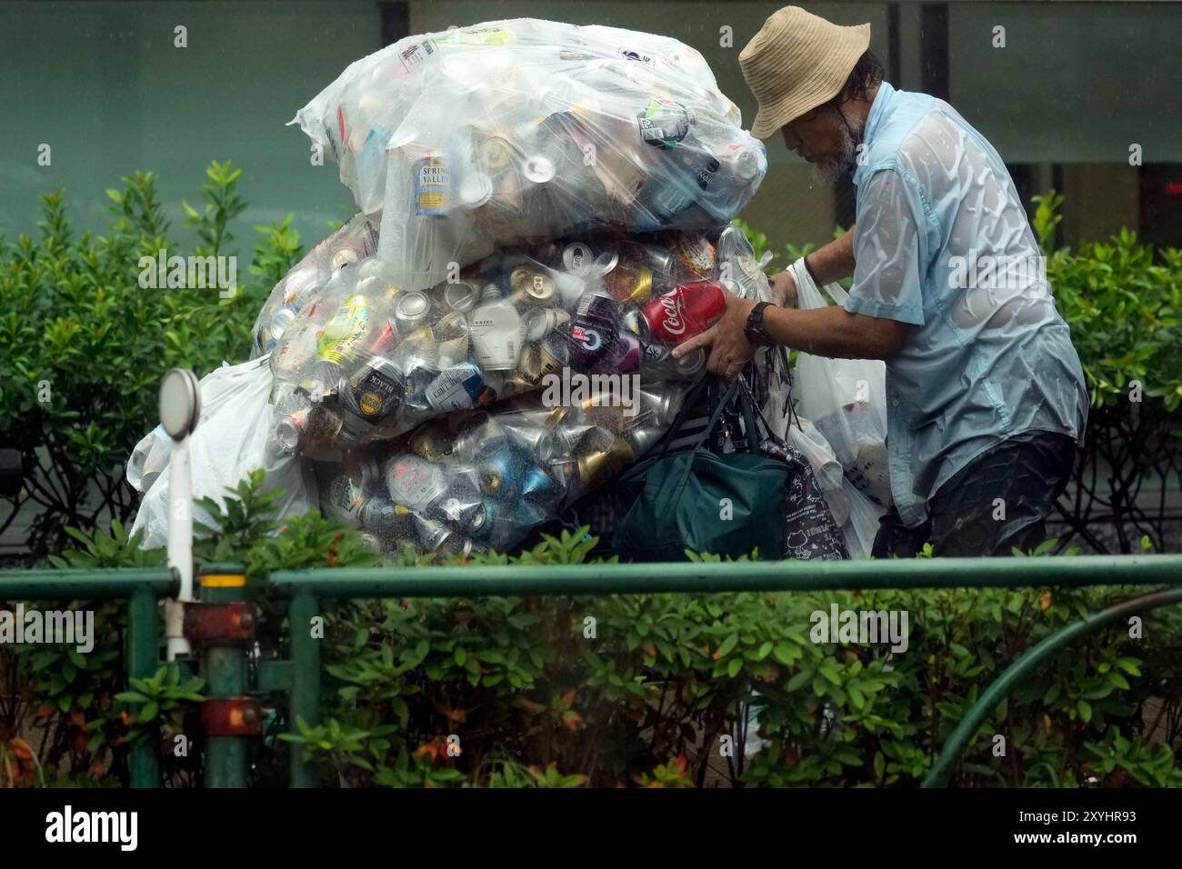An empty can collector carries cans in the heavy rain due to a severe ...
