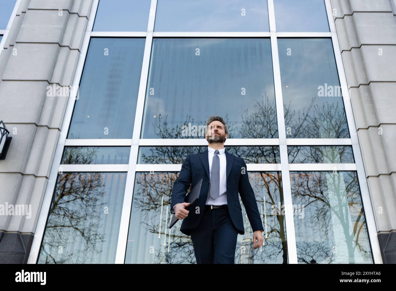 Confident business man standing outdoor on modern office building ...