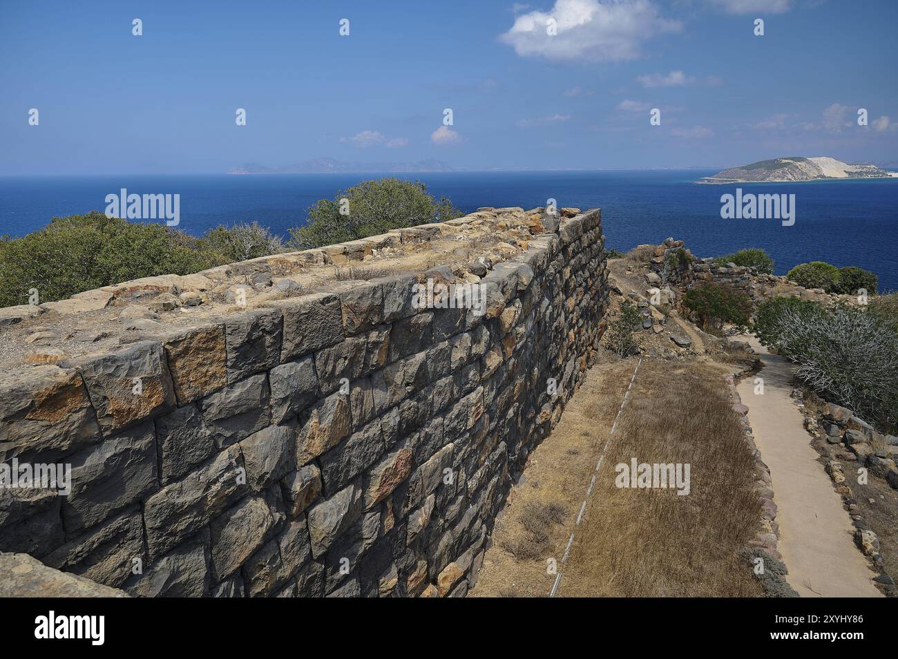 Ruin wall in an arid landscape with a view of the sea and a coastline ...
