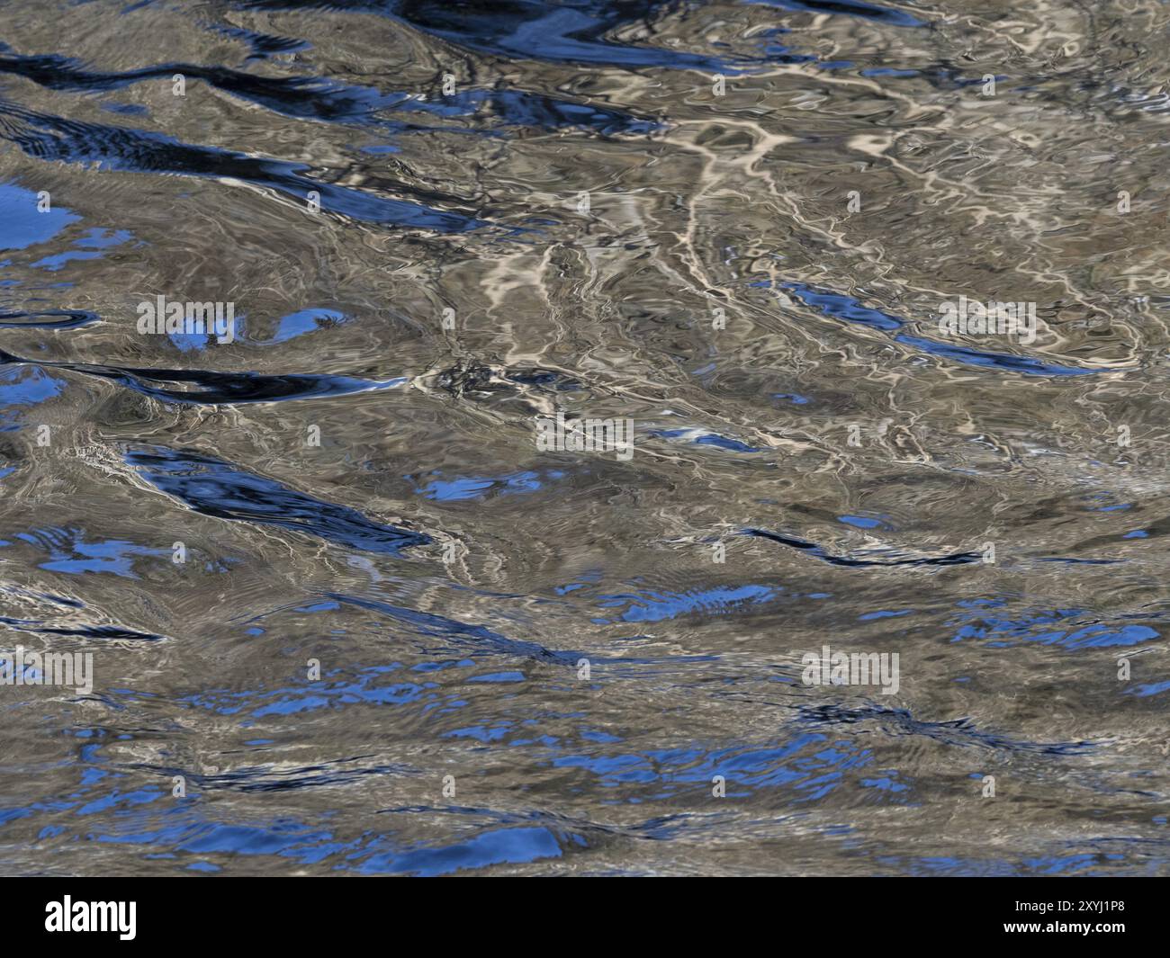 The colours of the blue sky and the trees on the banks are reflected in ...