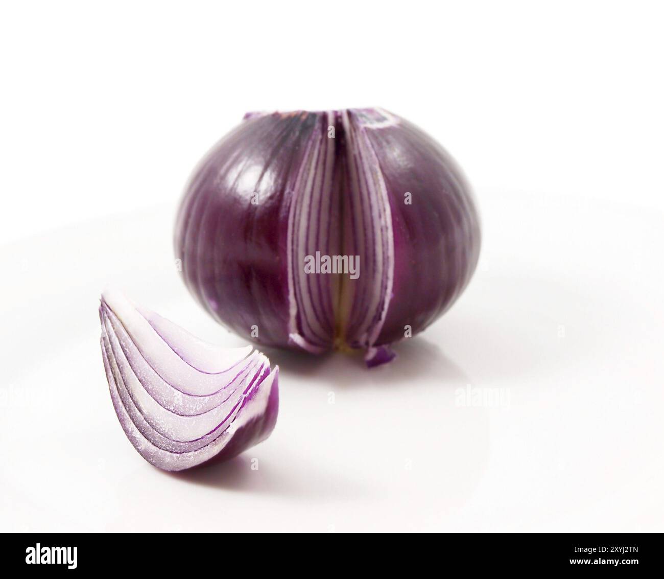 Red onion, whole, one slice up front in focus, towards white background ...