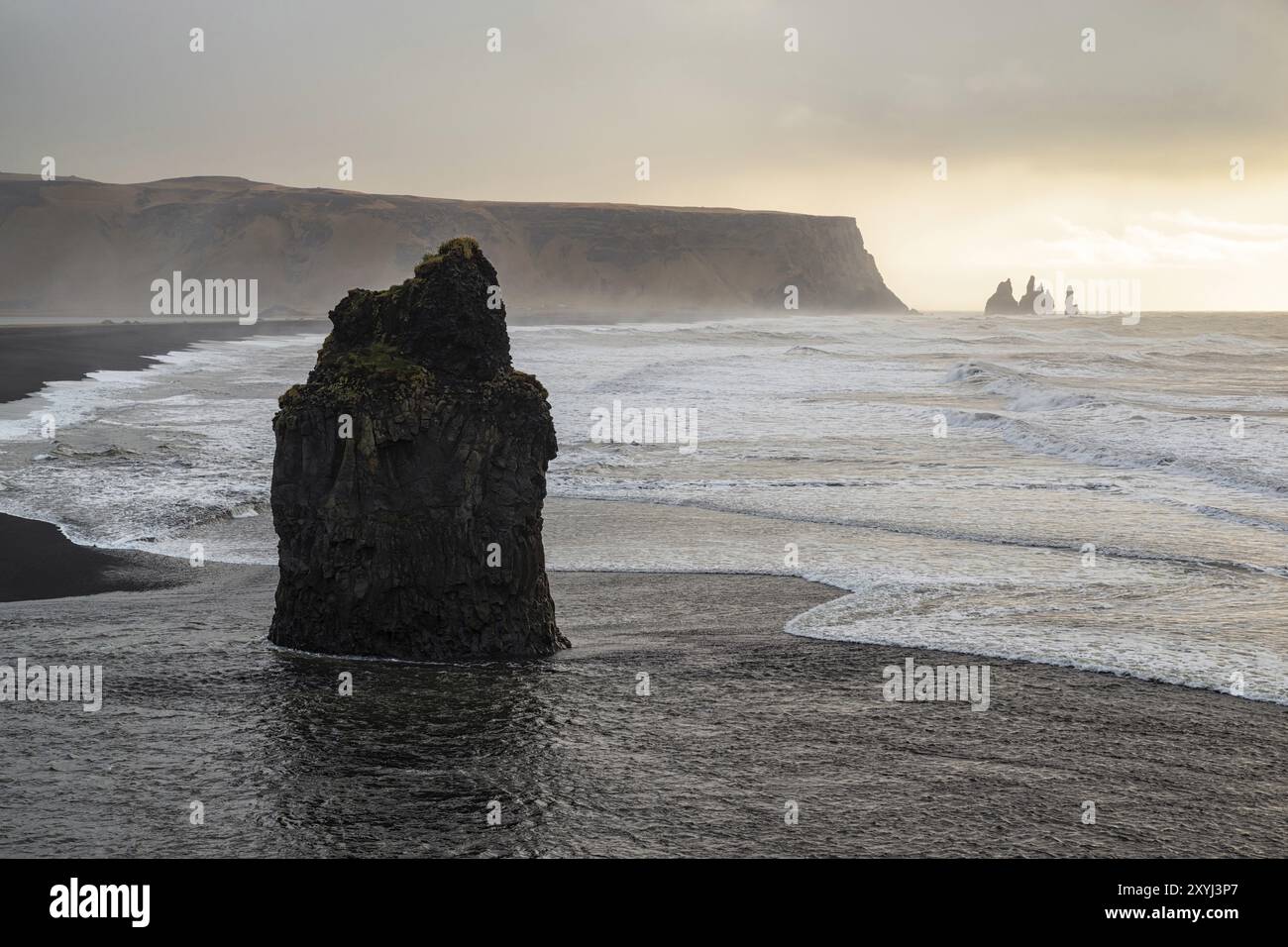 Rock formation on a black volcanic beach at Dyrholaey at sunset ...