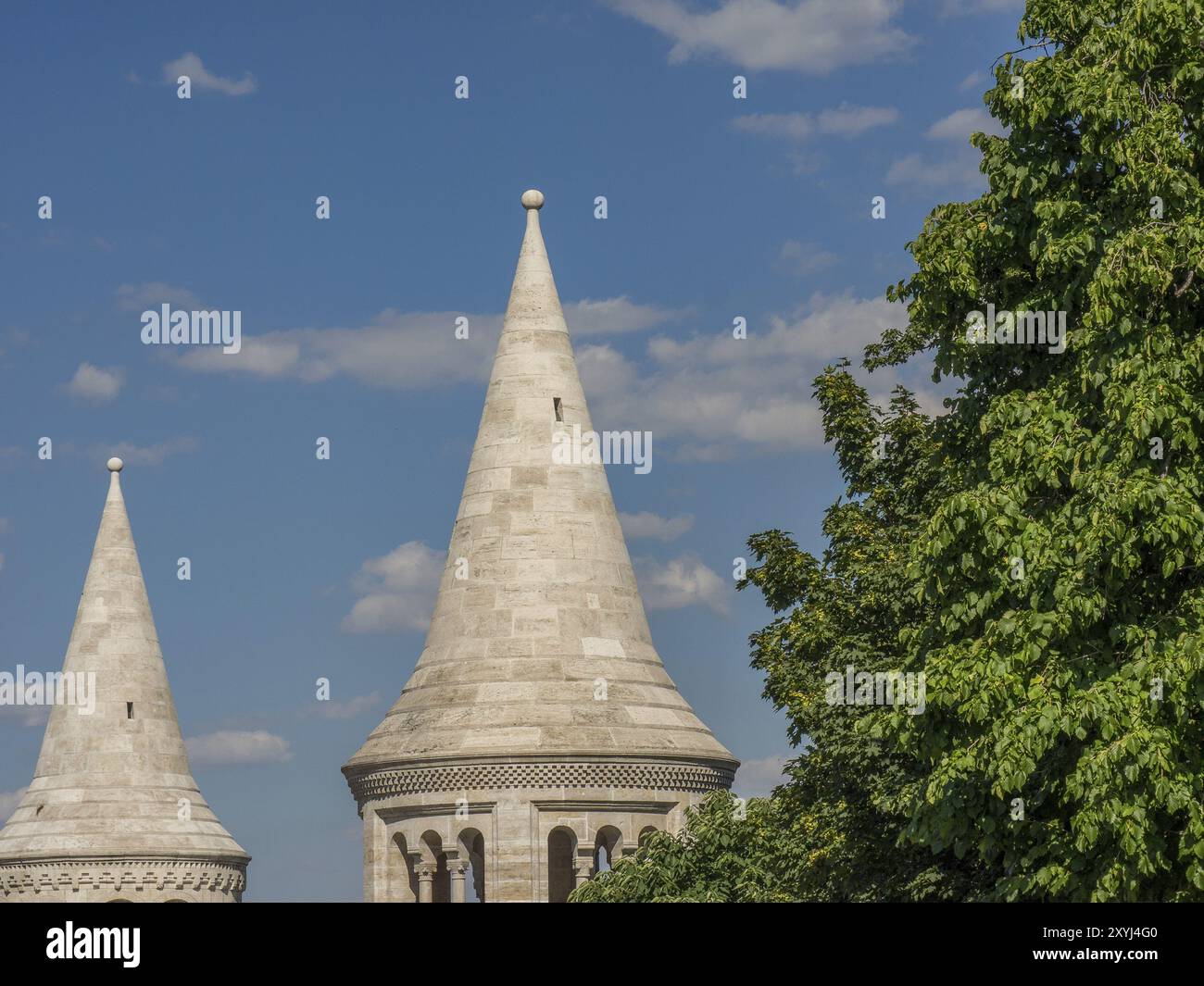 Historic towers surrounded by green trees and blue sky with few clouds ...