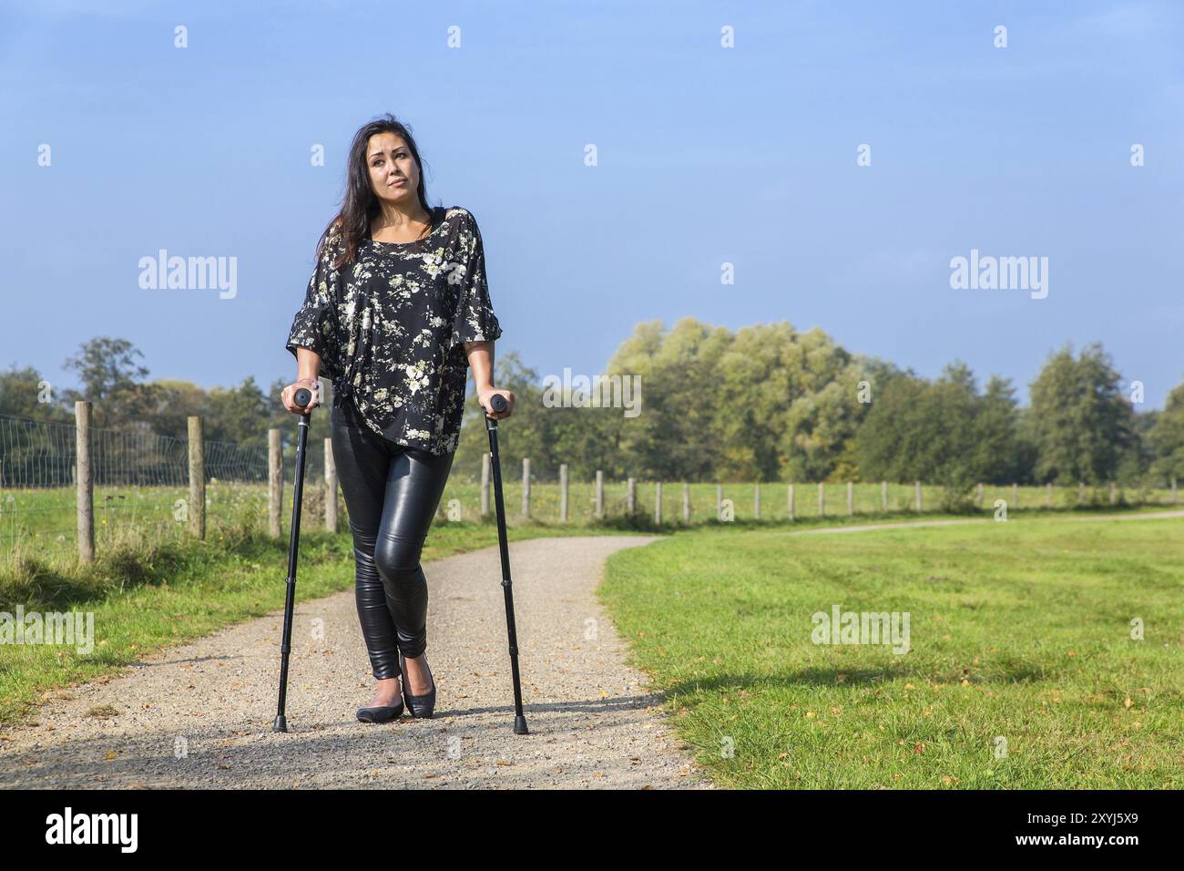 Disabled young woman walking on crutches in park Stock Photo - Alamy