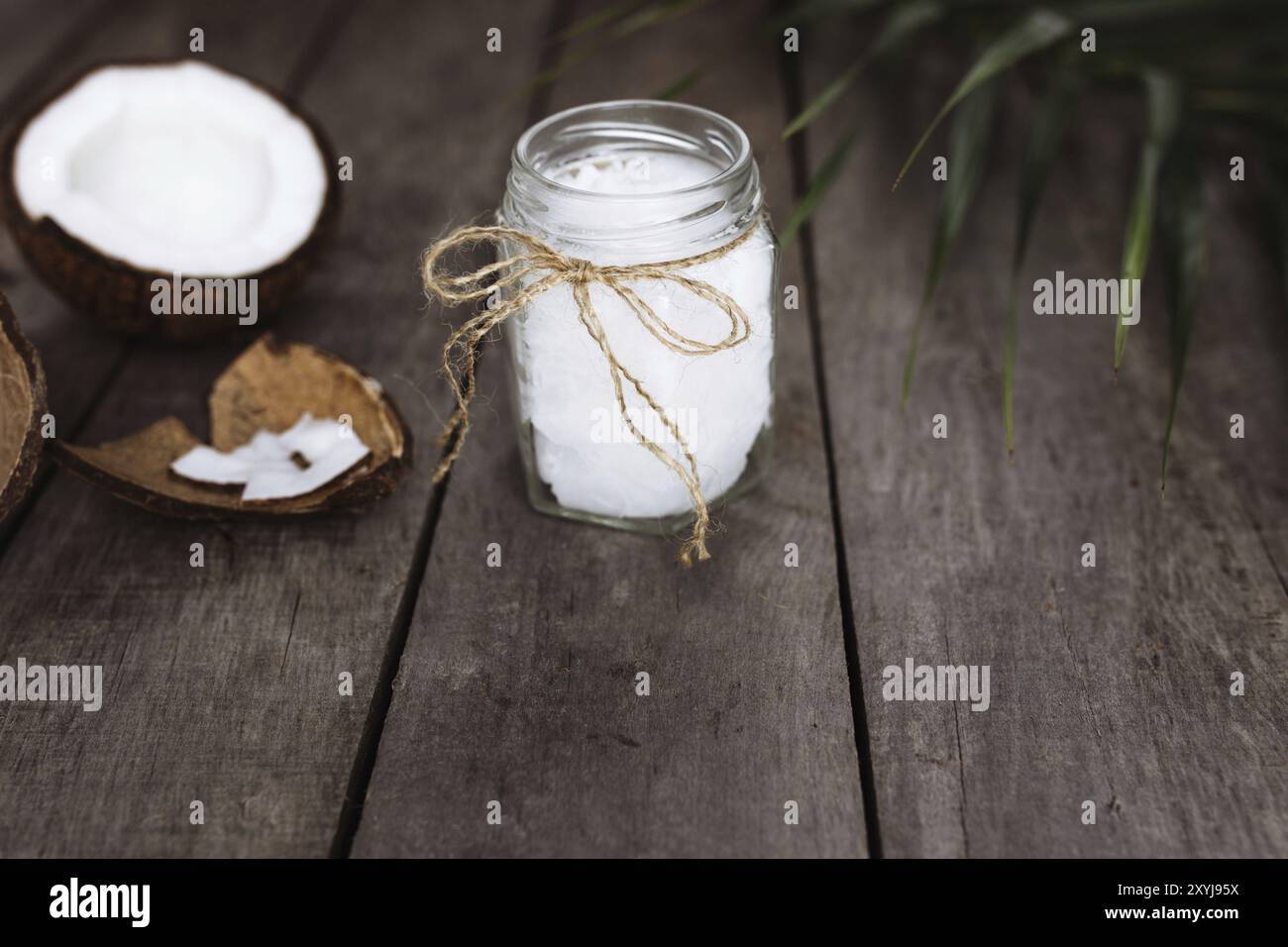 Broken coconuts on gray wooden background with jar of raw organic extra ...