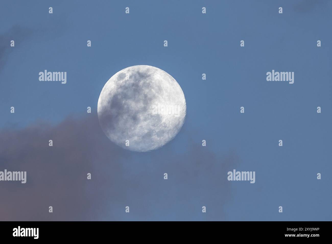 Full moon behind a cloud and blue sky Stock Photo - Alamy