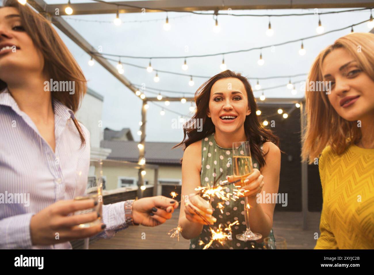 Group of partying girls with flutes with sparkling wine and bengal fire ...