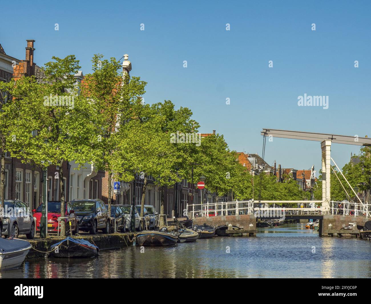 Quiet canal landscape with drawbridge, cars parked on the bank and ...