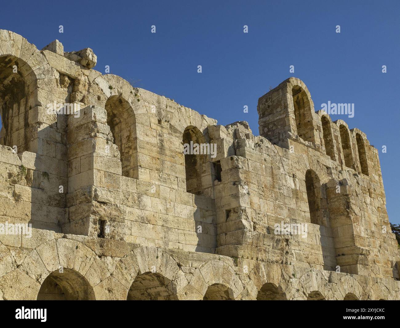 Ancient stone ruins with arches under a clear blue sky, athens, greece ...