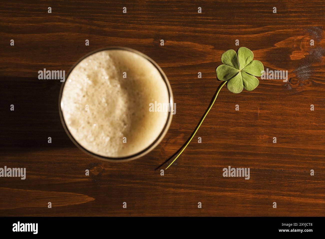 Pint of black beer and a shamrock on a wood background seen from above ...