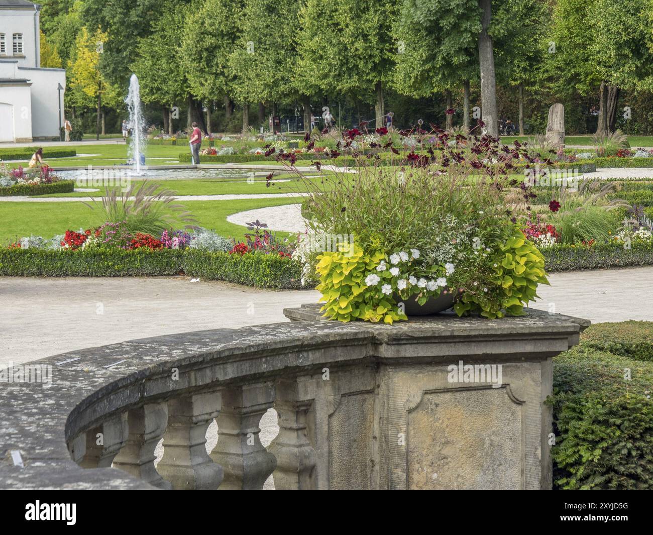 Extensive flowering garden with fountains, paths and trees in a well ...