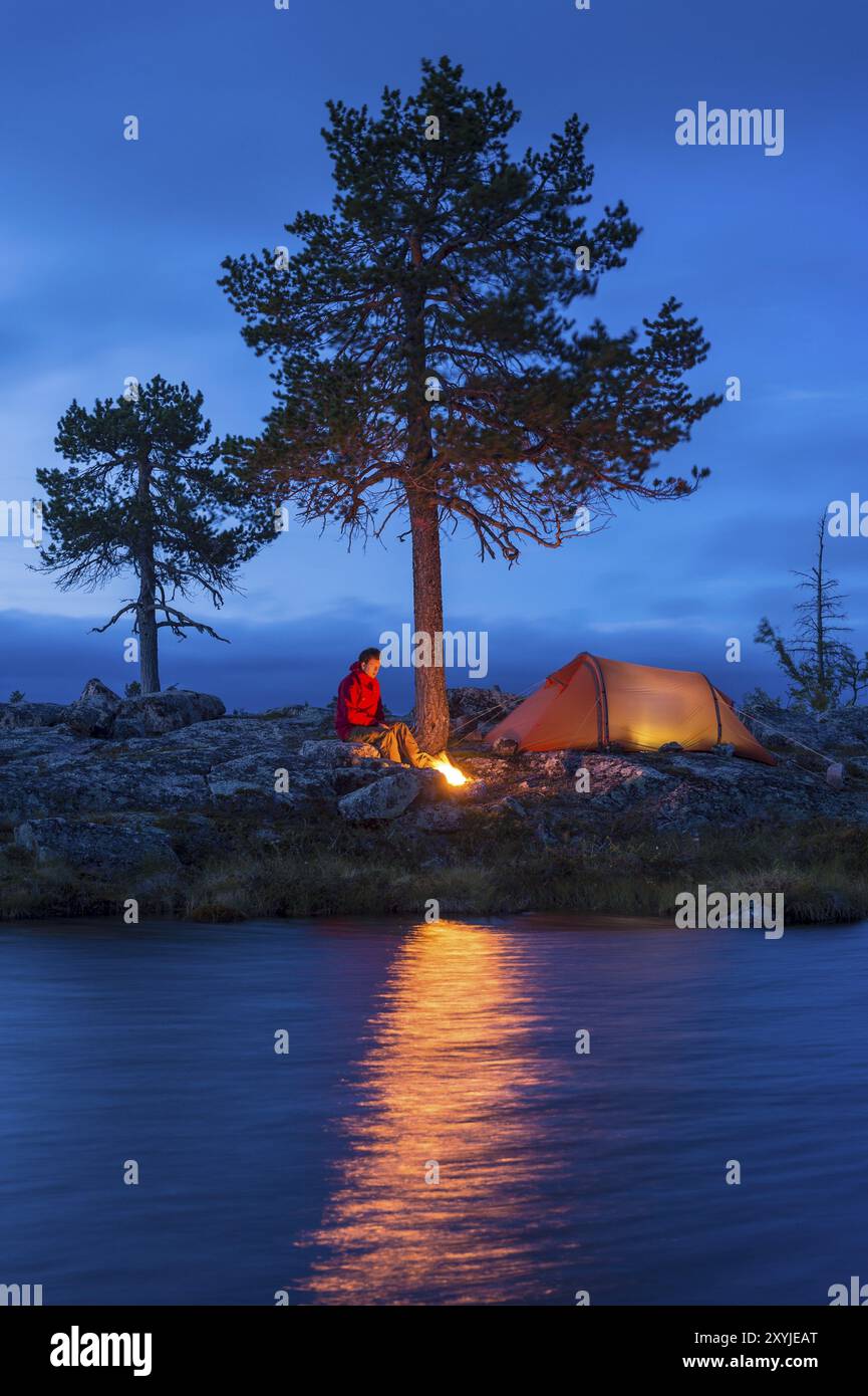 Man sitting by the campfire next to his tent, Norrbotten, Lapland ...